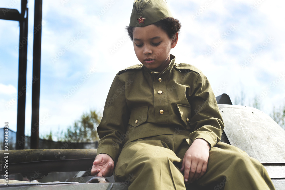 Boy in the military uniform on the tank of time of Second World War ...