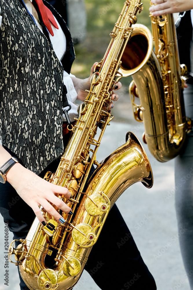 Two girls play a duet on golden saxophones in a summer park. Stock ...