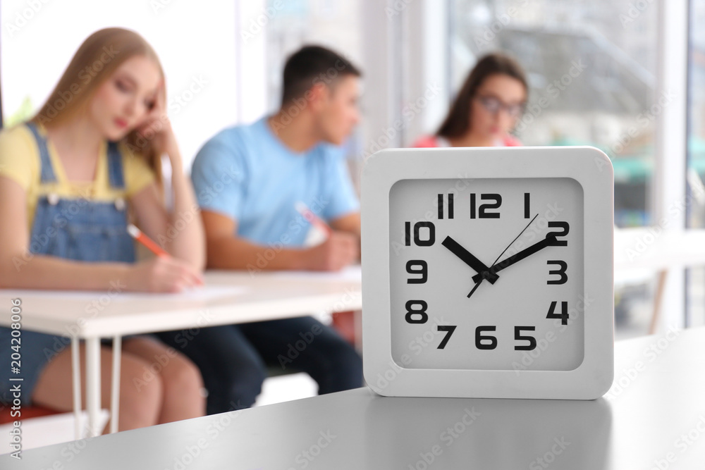 Clock and blurred students passing exam on background Stock Photo ...