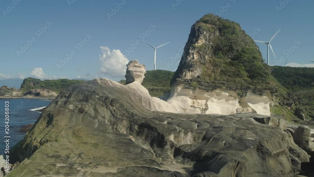 Natural rock formation of limestone stone on the coast with windmills ...