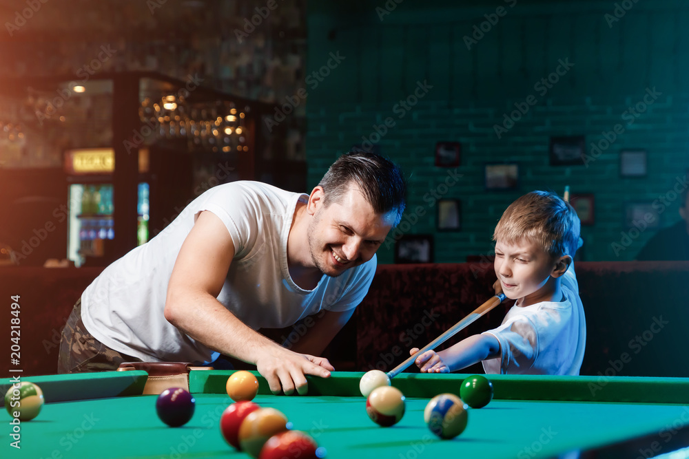 Father and son play billiards. The father teaches his son to play ...