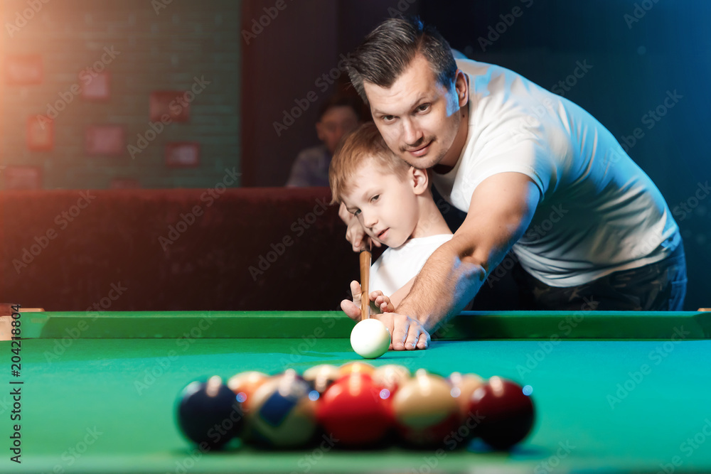 Father and son play billiards. The father teaches his son to play ...