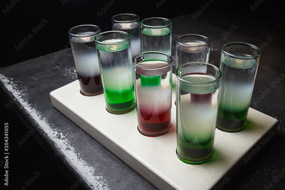 Eight shot glasses with rum, jager or cognac alcohol on a black ...