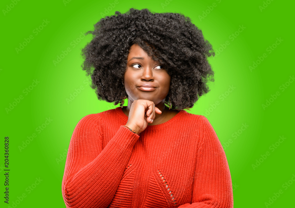Beautiful african woman thinking and looking up expressing doubt and ...