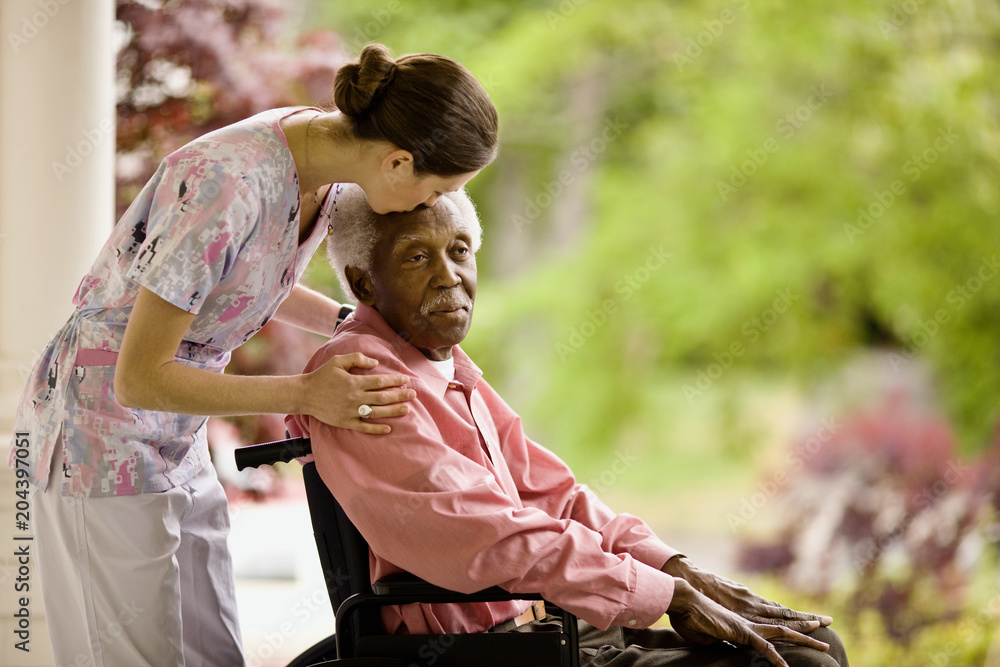 Nurse puts supportive hands on a senior man's shoulders and leans ...