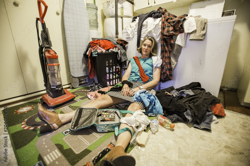 Overwhelmed mom or mother covered in laundry in front of laundry ...