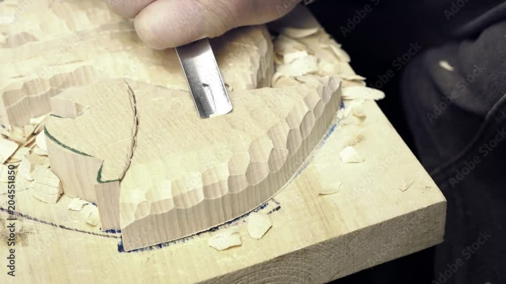Artistic wood carver cuts lime wood carving. Detail on craftsman's hand ...