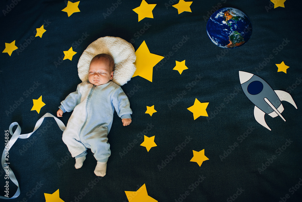 baby boy sleeps on the background of the starry sky with a rocket and ...
