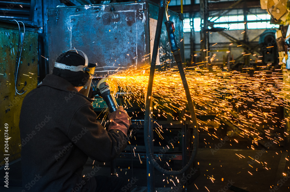 A man in working form and a face mask cuts a metal saw with a Bulgarian ...