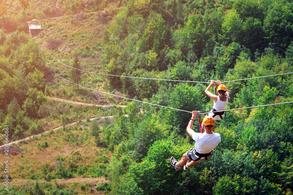 Zipline is an exciting adventure activity. Man and woman hanging on a ...
