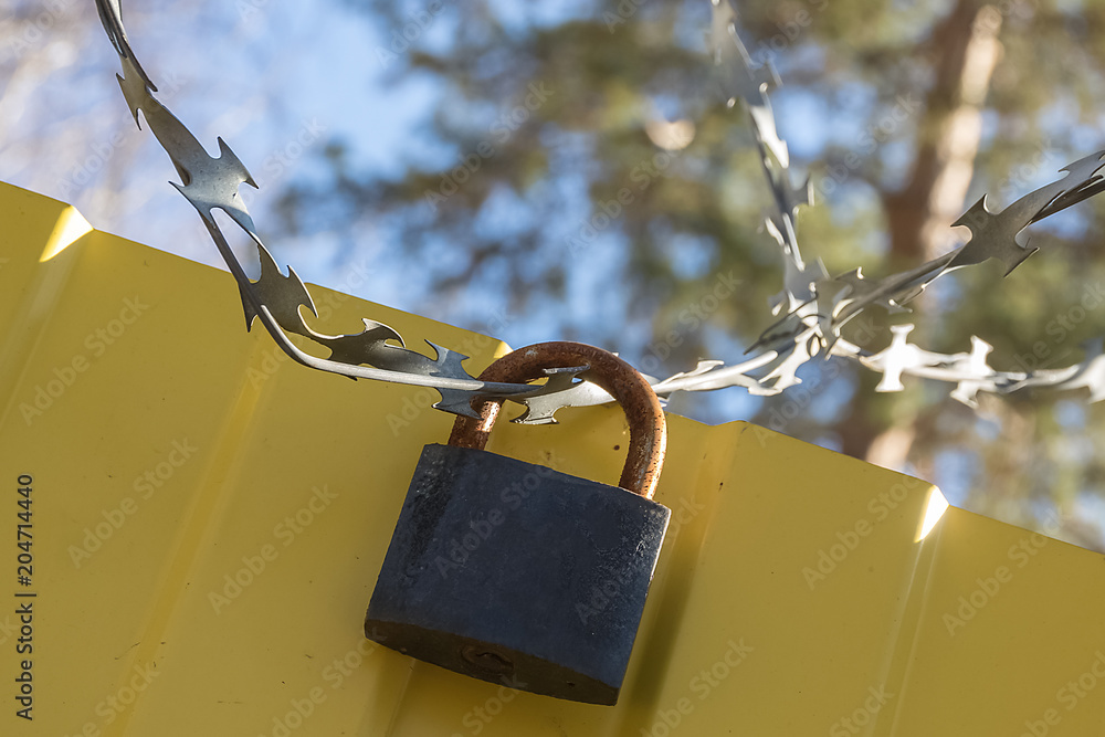 barbed wire on top of fence, lock hanging on wire, forbidden zone, stop ...