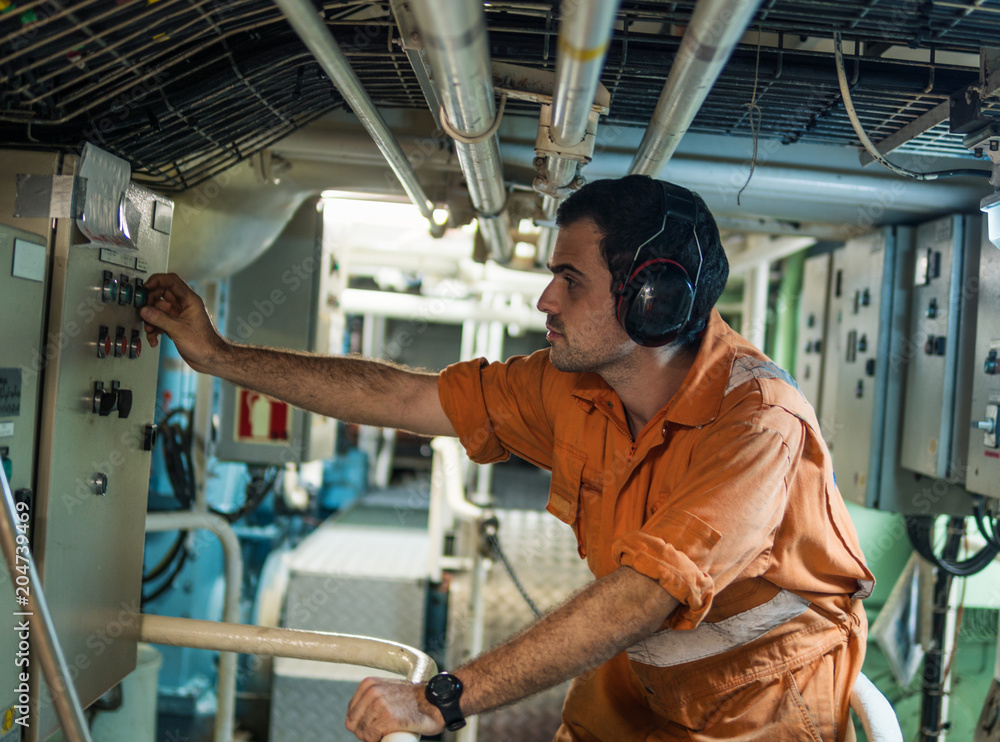 Marine engineer inspecting ship's engine in engine control room ECR ...