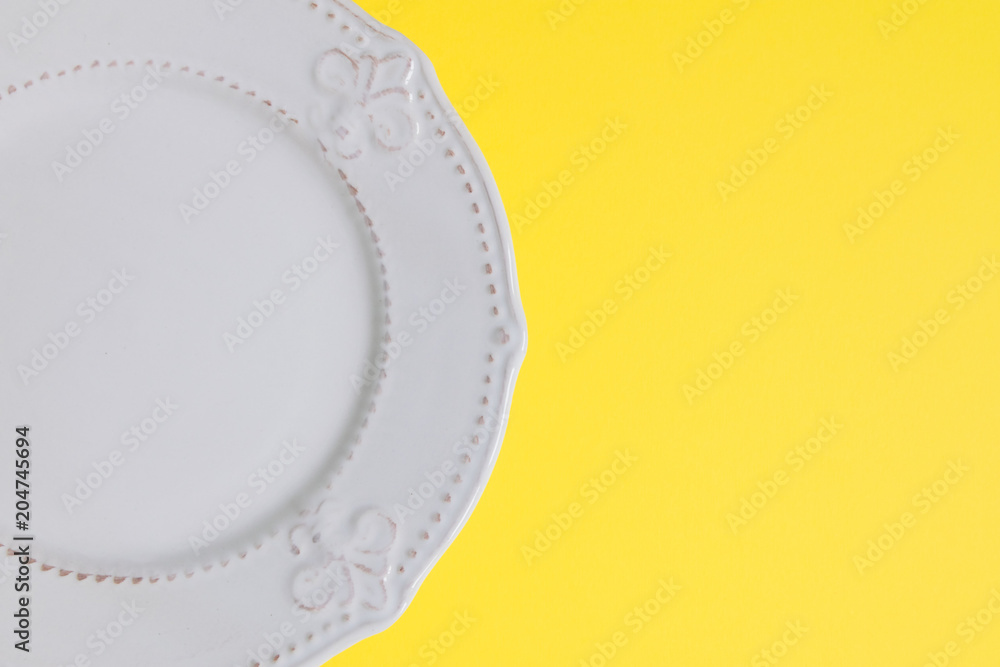 Half white rustic plate on yellow background. Plate on the left side of ...