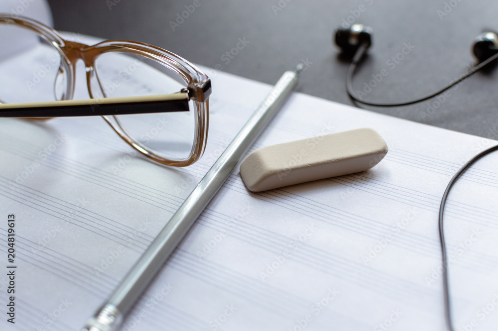Side view of the gray pencil, eyeglasses, black earphones and eraser ...