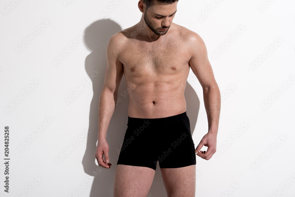 Youn shirtless healthy athletic man is standing against light ...