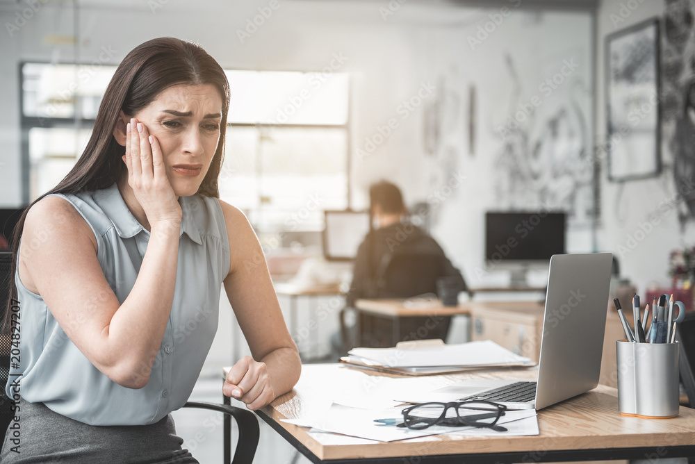 Portrait of disillusioned lady feeling pain in tooth while working with ...