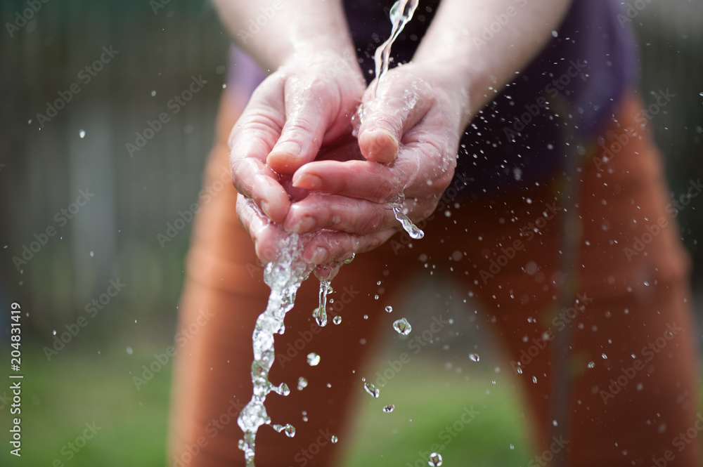 Woman washing hand outdoors. Natural drinking water in the palm. Young ...