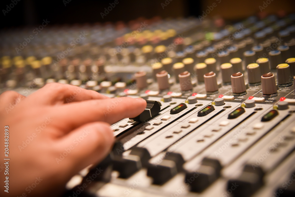 close-up hands of sound engineer adjusting audio mixer controller for ...