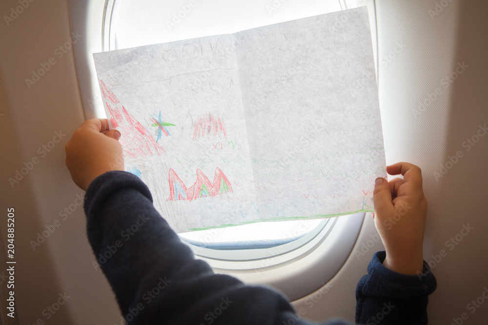 Child putting his drawing in the window of the plane Stock Photo ...