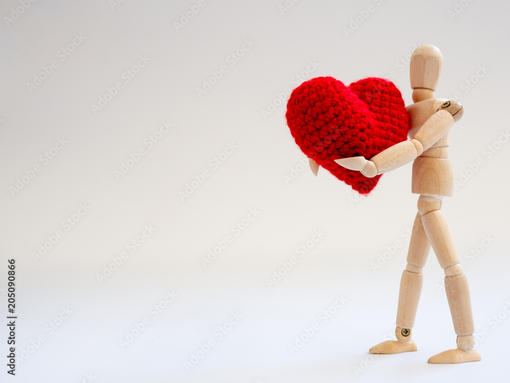 Wooden puppet standing and holding a red heart on the white screen ...