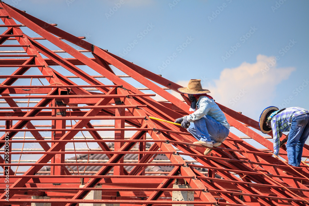 welder workers installing steel frame structure of the house roof at ...