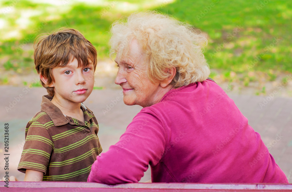 Mature woman communicating with the boy in the park. Grandmother and ...