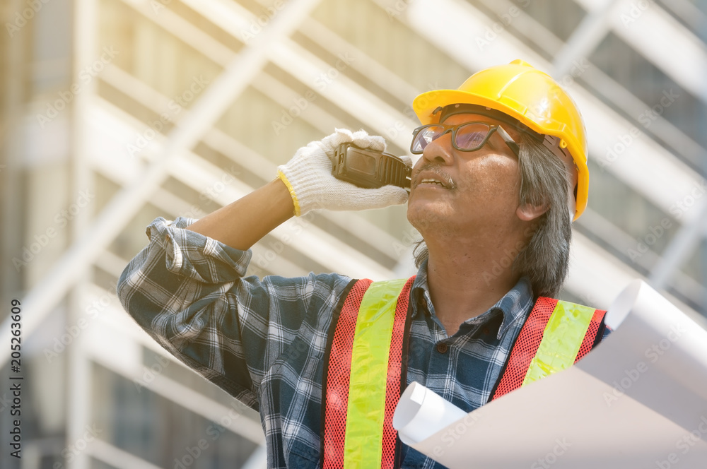 Senior Asian civil engineer wearing safety helmet using radio walkie ...