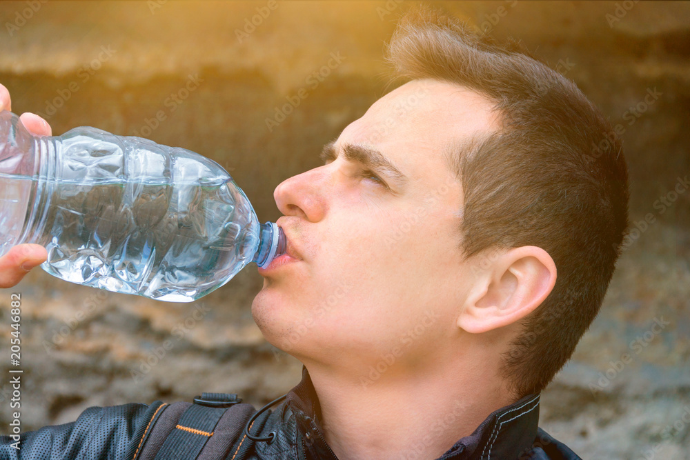 The guy drinks water from a plastic bottle, thirst quenching, mineral ...