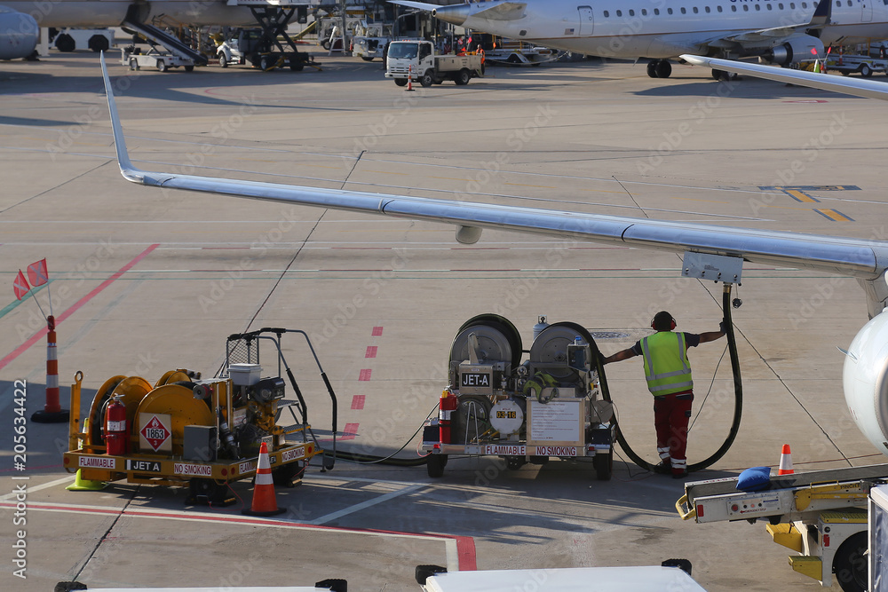 Aircraft at terminal, and ground crew refueling aircraft after taxing ...
