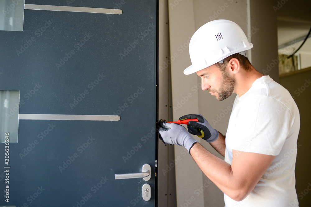 handsome young man installing a door in a new house construction site ...