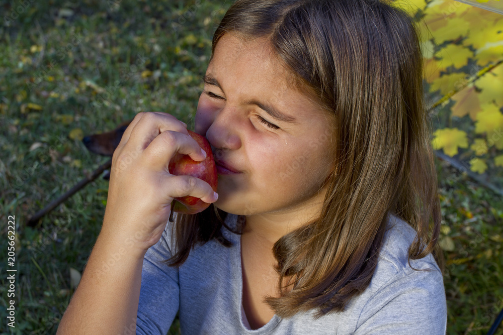 Child bite a red apple and has a heavy toothache. Cute little girl eat ...