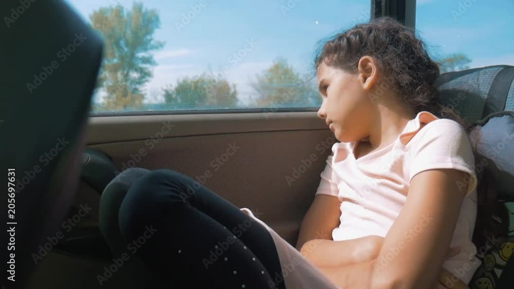 sad girl bored sitting in the car in the back seat motion travel ...