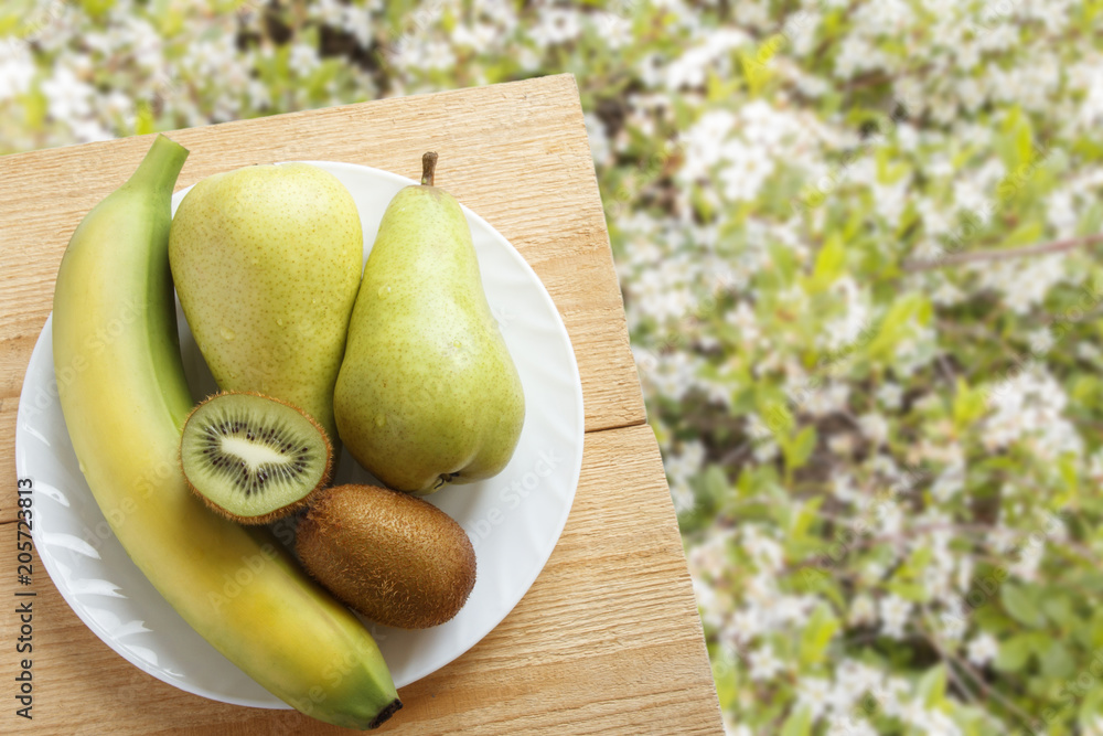 Fresh banana, kiwi fruit and pear on wooden table on background of ...