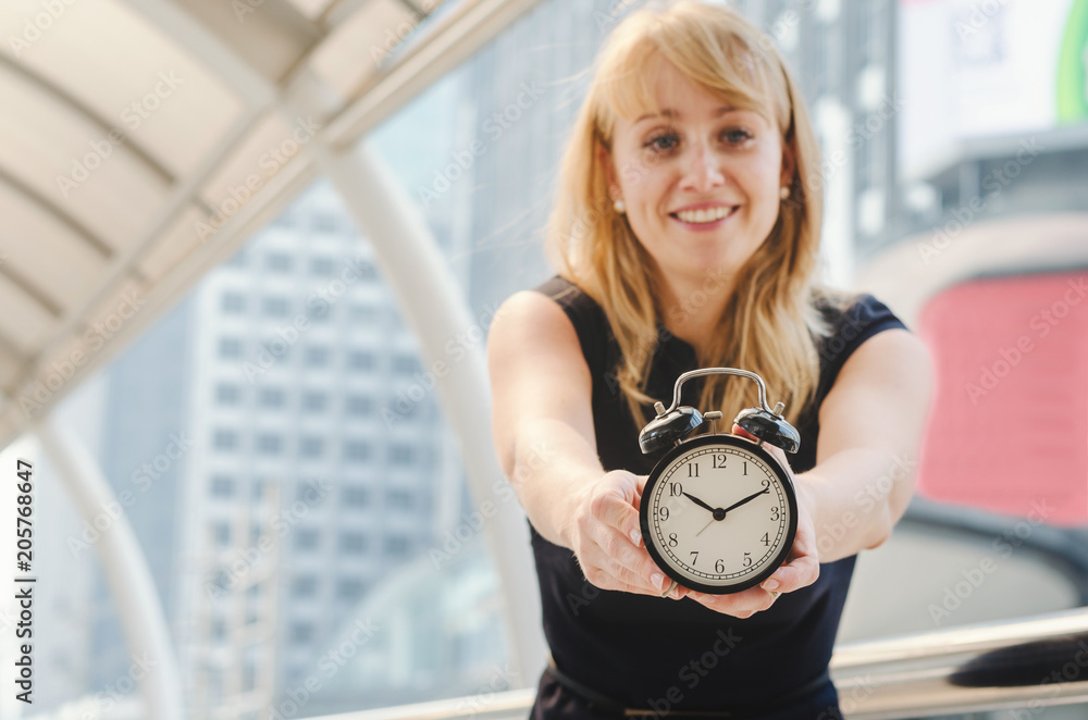 beautiful woman confused with time holding the alarm clock at 10 minute ...
