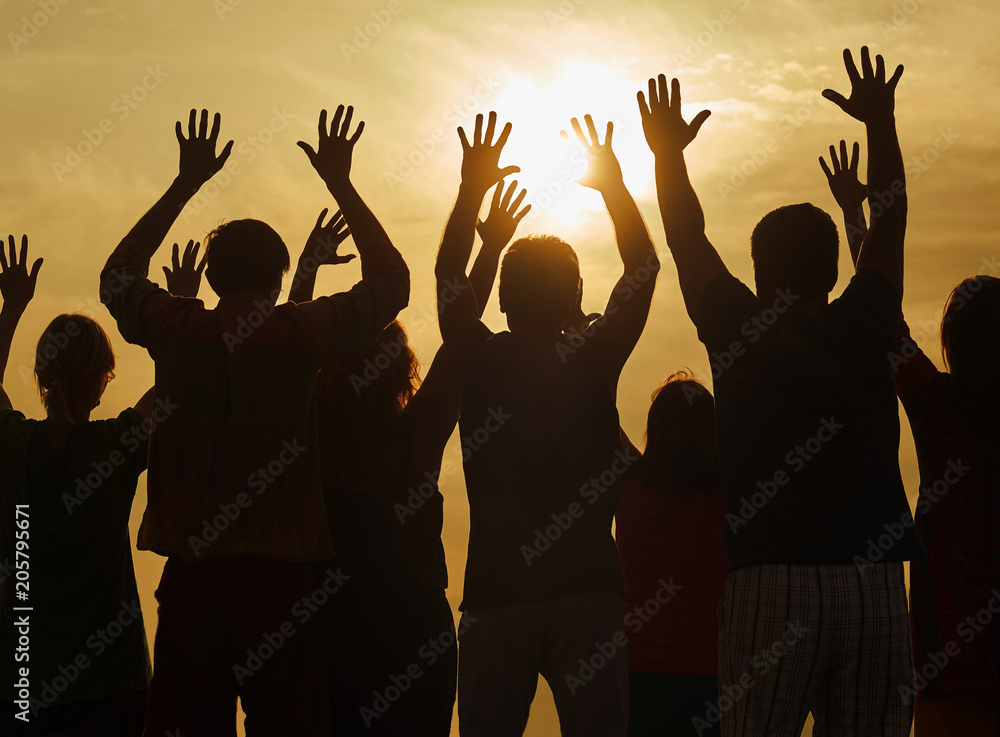 People silhouette over sunset sky. Family standing and raise their ...