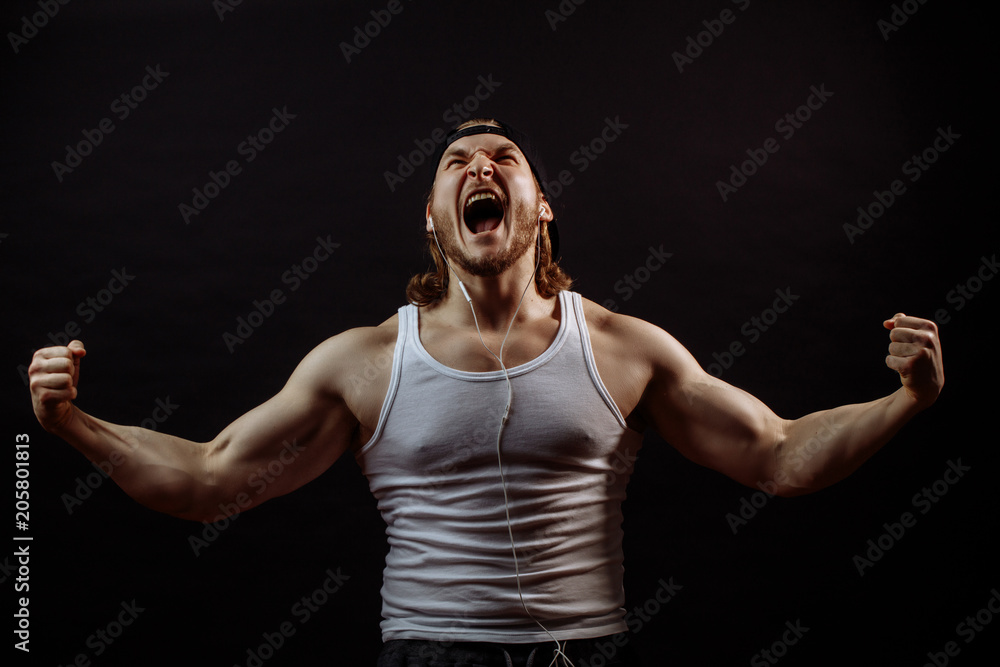 joyful bodybuilder in white singlet and black cap. cry at the top of ...