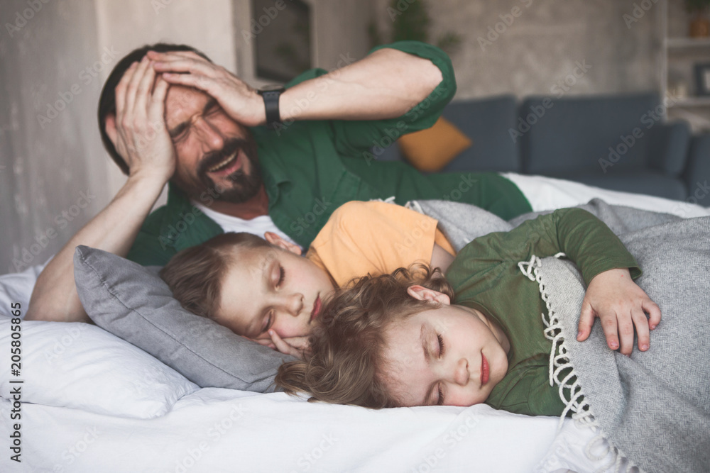 Oh no. Portrait of unhappy father keeping head by hands while lying ...