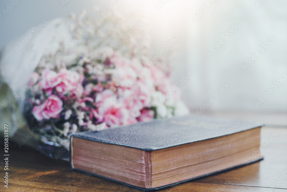 Holy bible with flowers on wooden table background against window light ...