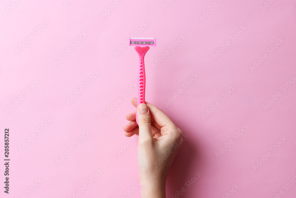 razor in a female hand on a colored background. Removal of unwanted ...