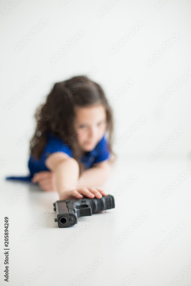 Child reaching for hand gun in white room Stock Photo | Adobe Stock