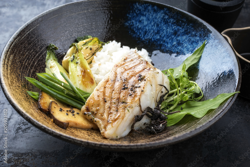 Modern Japanese fried cod fish filet with bok choi and rice as top view ...