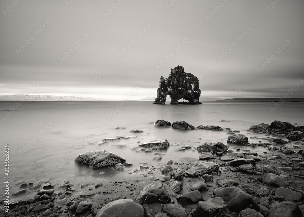 Scenic view of a striking rock formation in shallow water on a beach ...