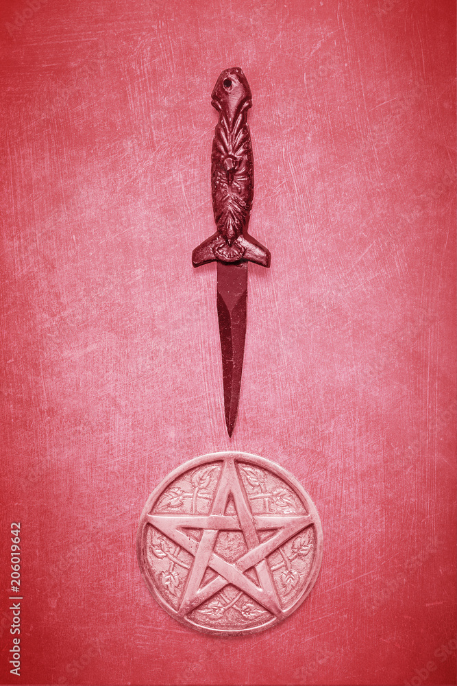 Red Wiccan dagger and pentagram on a textured red background with space ...