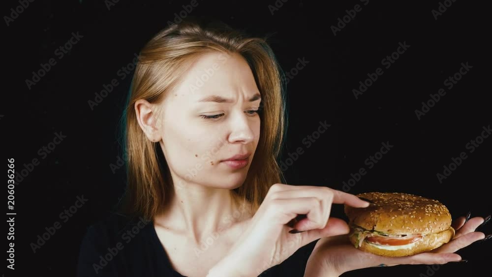Bad hamburger. Poor food. The girl looks at the hamburger in disgust ...