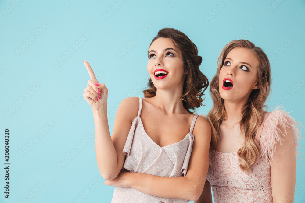 Two beautiful girls 20s wearing party outfit pointing index fingers ...