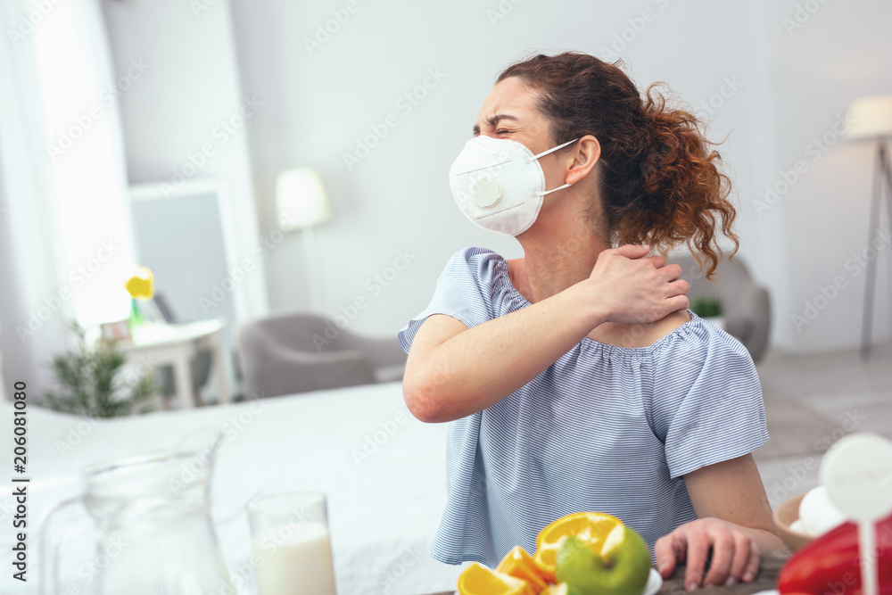 Food allergy symptoms. Young sore looking woman in a respiratory mask ...