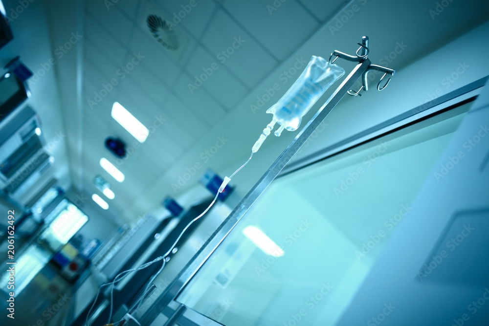 Hospital building corridor with intravenous drip bag on the steel pole ...