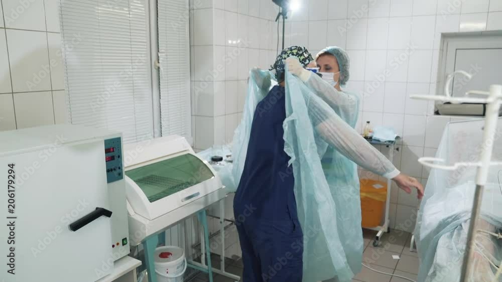 The doctor enters the operating room. A nurse helps to dress a doctor's ...