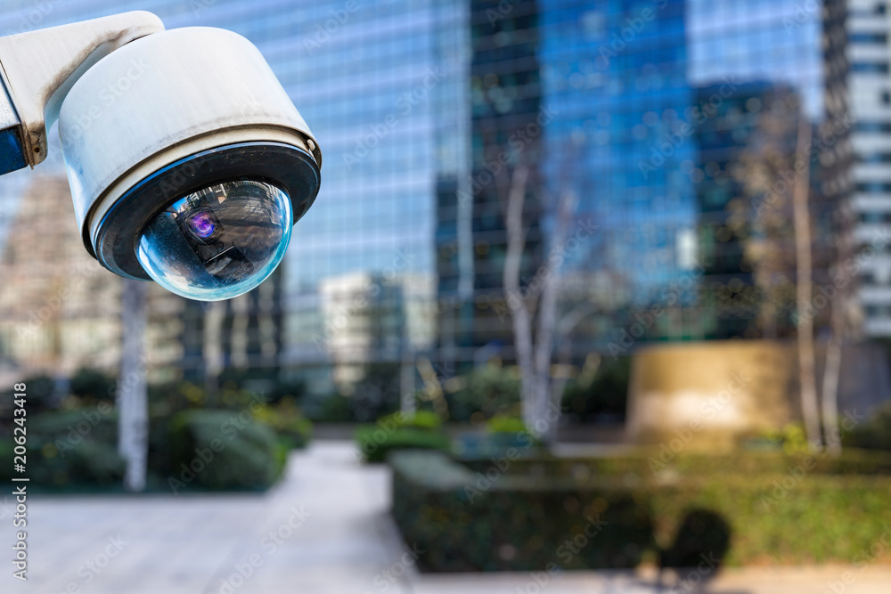 security CCTV camera or surveillance system with buildings on blurry ...