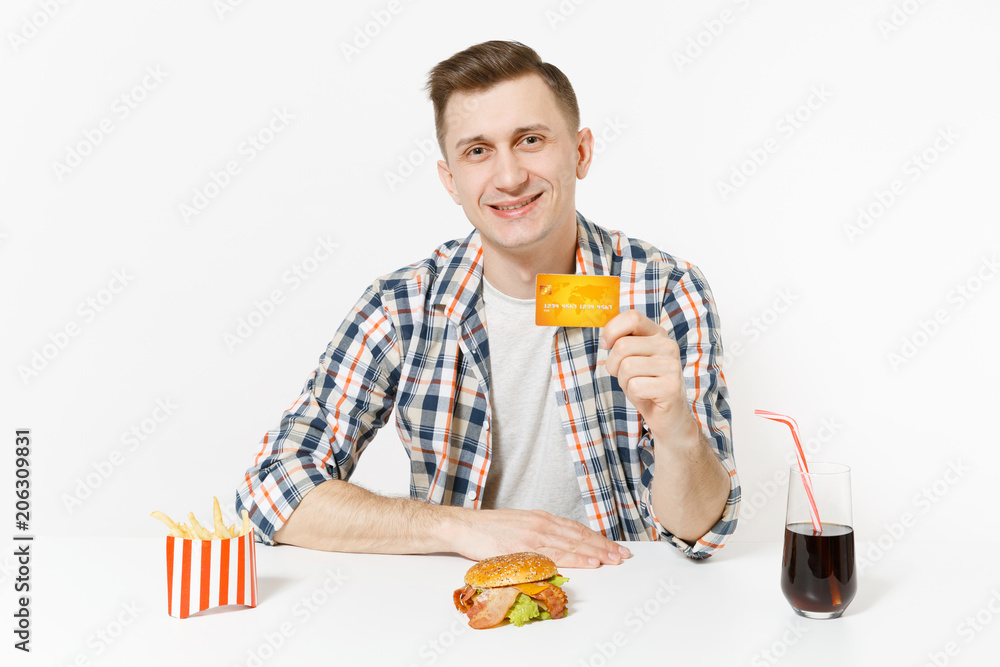 Handsome young man sitting at table with credit card, burger, french ...